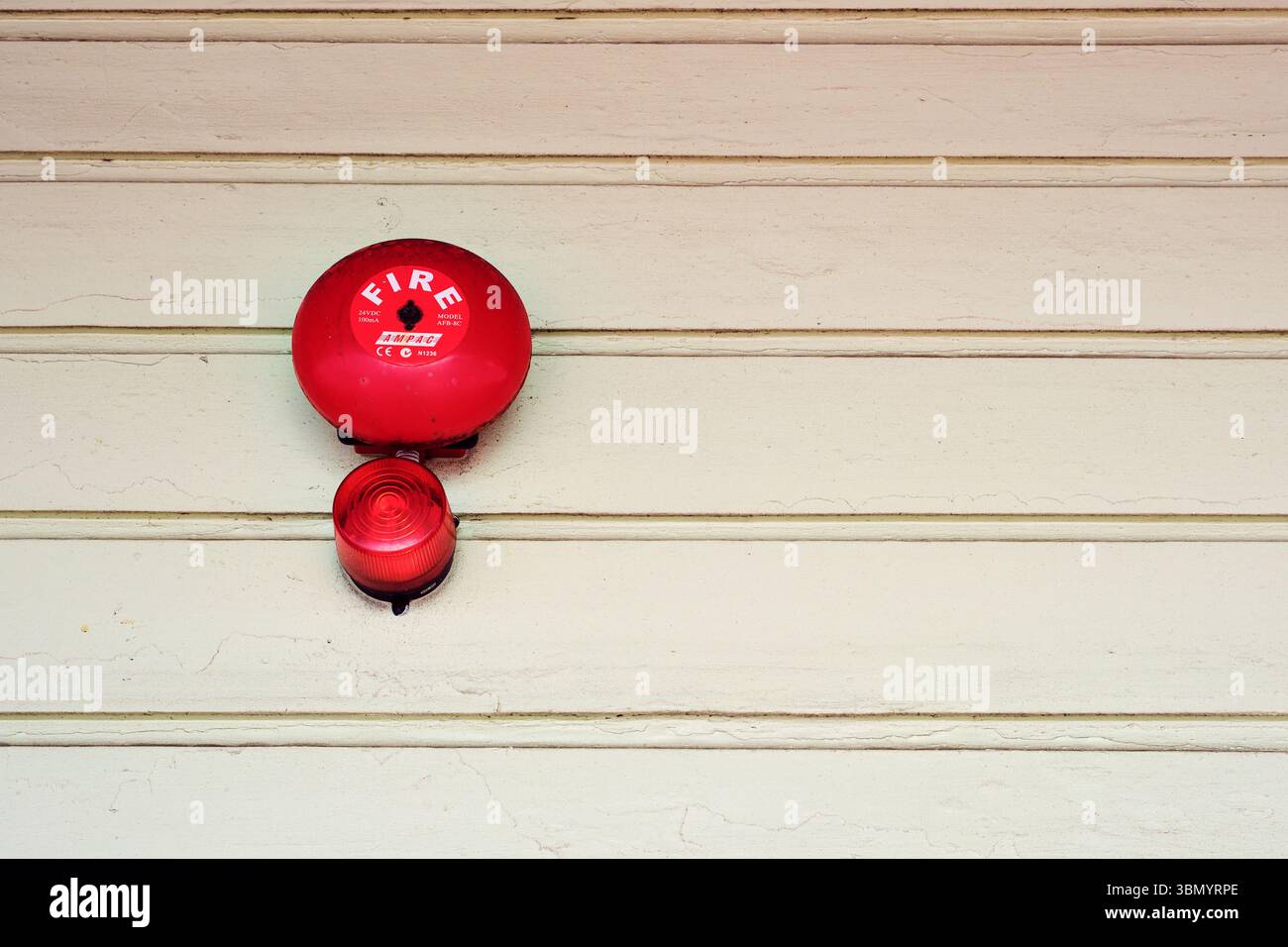 A red fire alarm bell and light mounted on the exterior wall of a ...