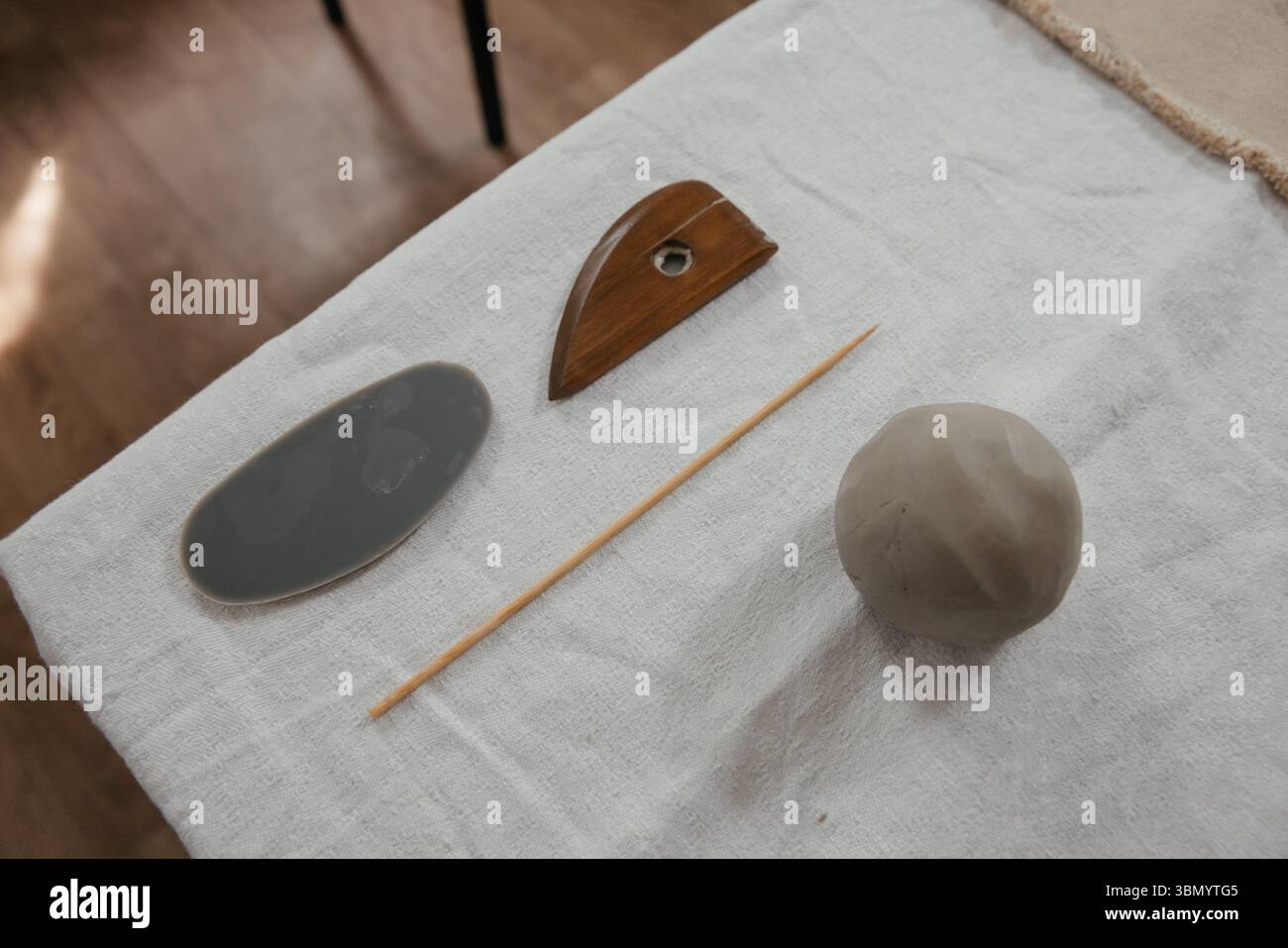 Round clay lump and ceramic hobby tools set on rustic table for pottery ...