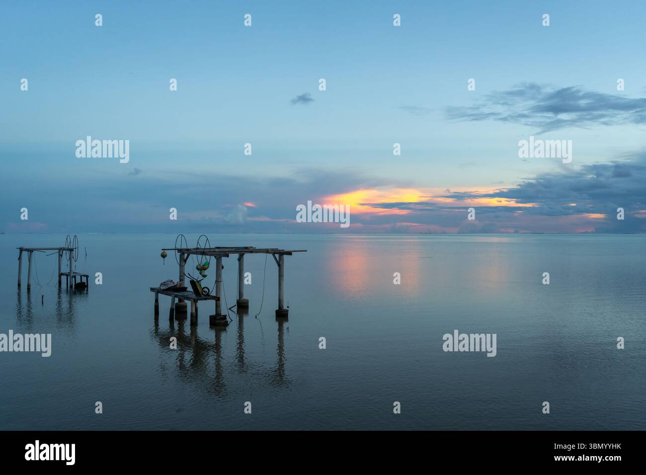 A beautiful sunrise reflects on the calm lagoon of Maupiti, French ...
