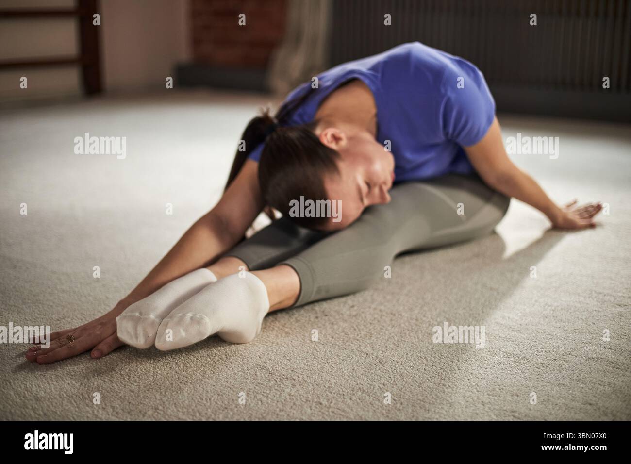 Caucasian young adult woman stretching on floor during rhythmic ...
