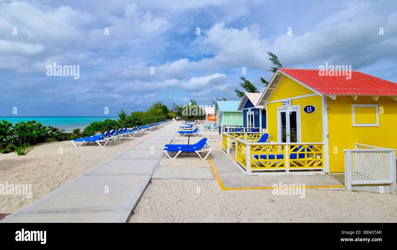 Colourful bungalows and blue lounge chairs on the shores of the ...
