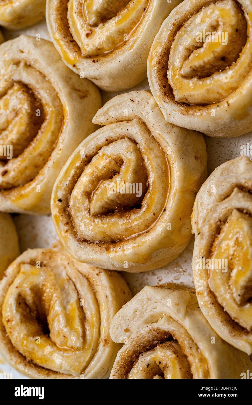 Making homemade cinnamon puff pastry buns. Raw dough rolls greased with ...