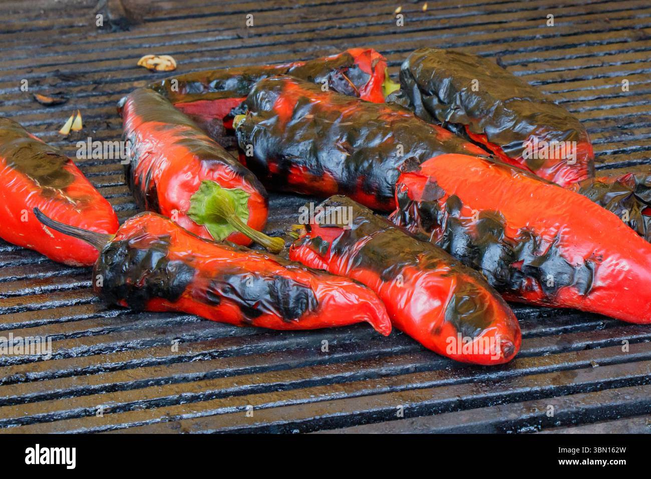 Vibrant red peppers are grilling on a barbecue, showcasing a smoky char ...