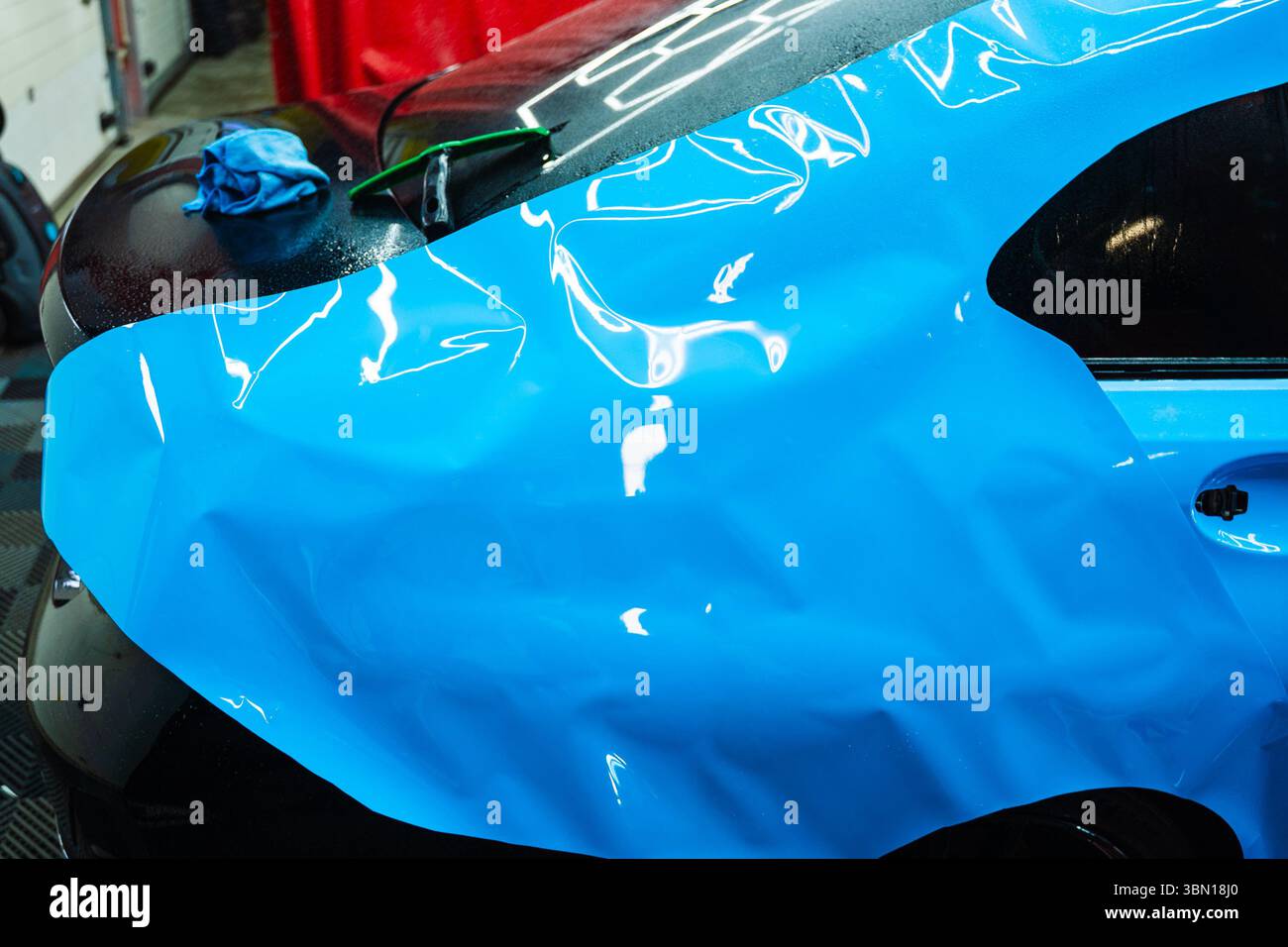 Applying PPF wrap on car during full detailing. Bold blue vinyl wrap ...