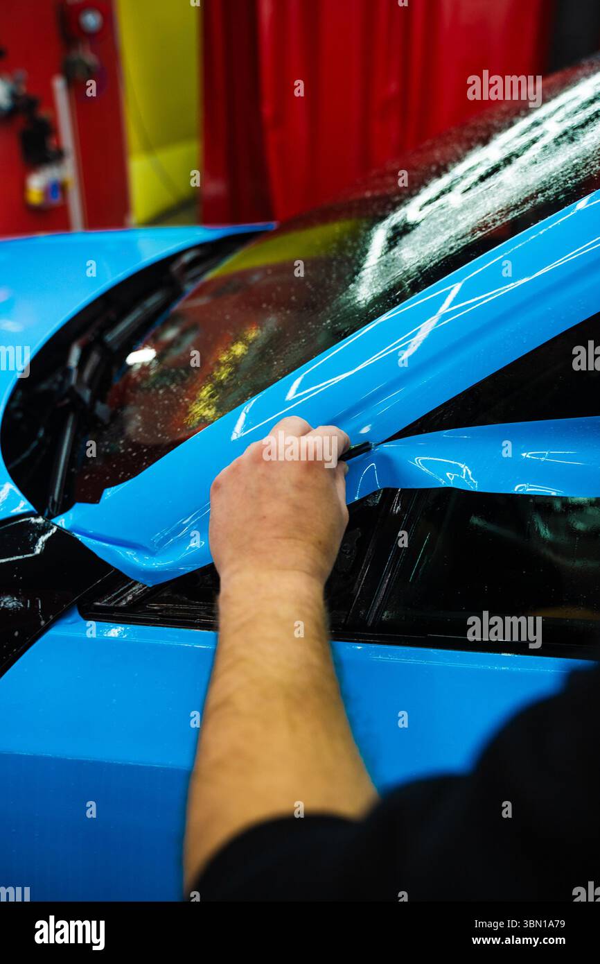 Cutting blue PPF with blade. Cutting blue paint protection film with ...