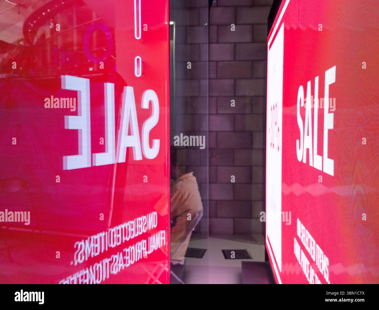 A large LED screen displaying a bold red and pink sale sign illuminates ...