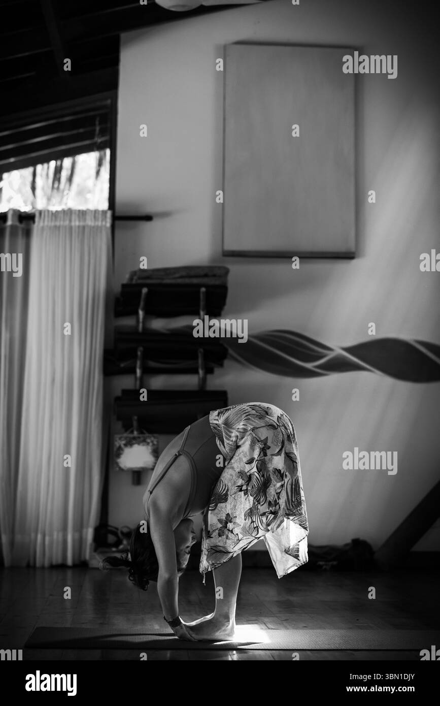 Woman Practicing Standing Forward Bend Yoga Pose Indoors with Floral ...