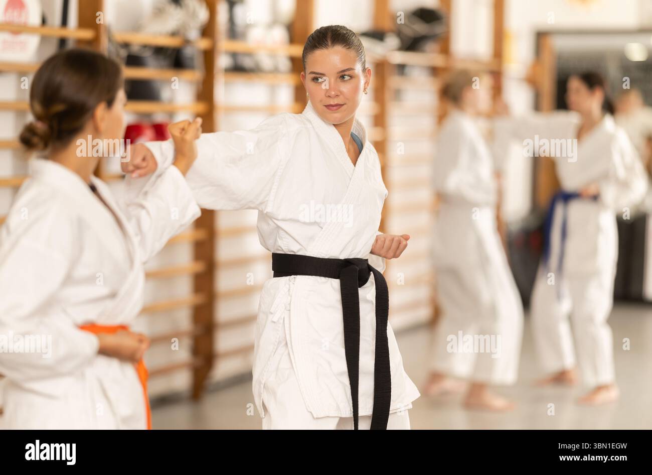 Young female attendee of karate classes fighting with partner in sports ...