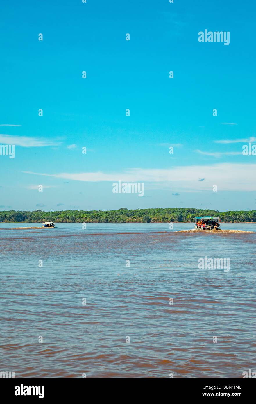 Two boats navigate the muddy waters of the Amazon River in Leticia ...