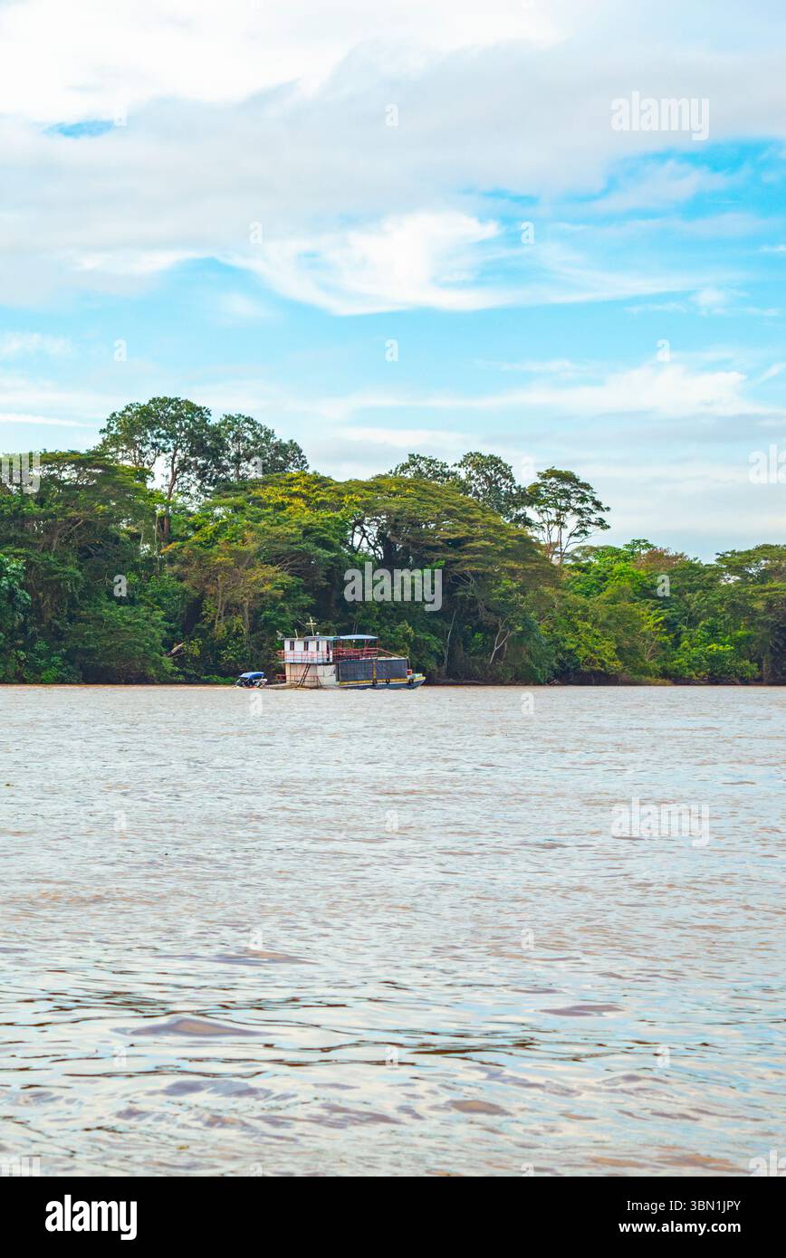 A tranquil view of the Amazon River with a boat and lush trees in ...