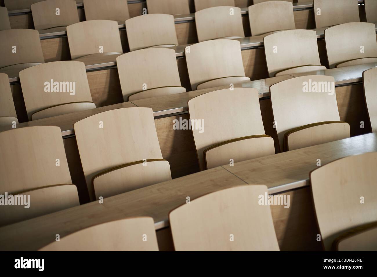 Empty lecture hall seating showing rows of unoccupied wooden chairs in ...