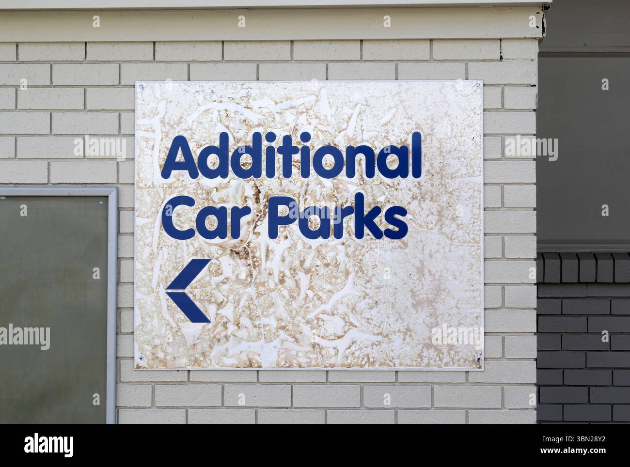 Old and weathered Additional Car Parks sign attached to a brick wall ...