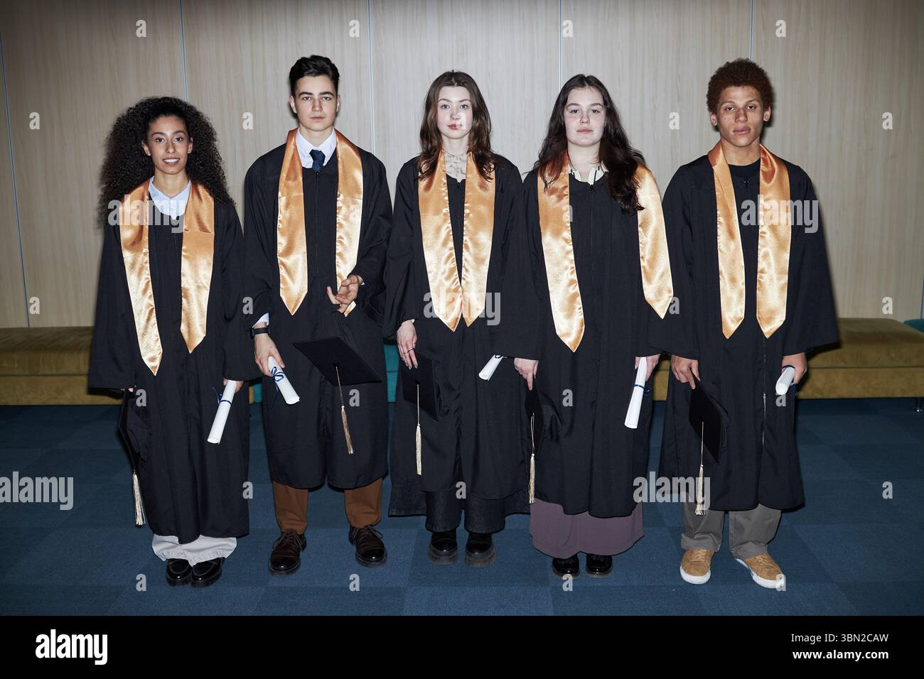 Group of five multiethnic teenagers standing in graduation gowns ...