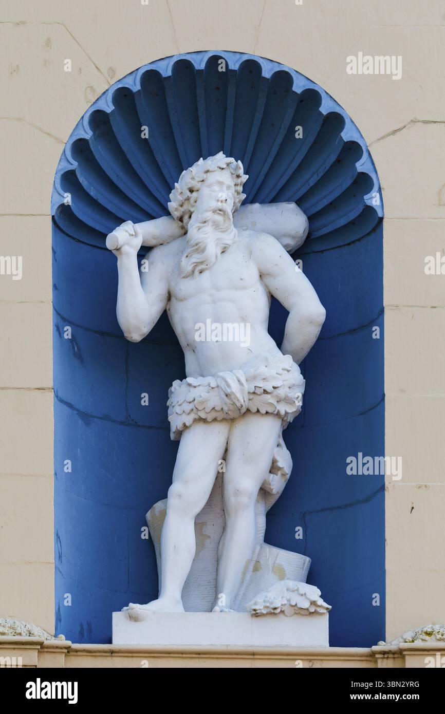 White statue of Greek God with bat in blue alcove of building Stock ...