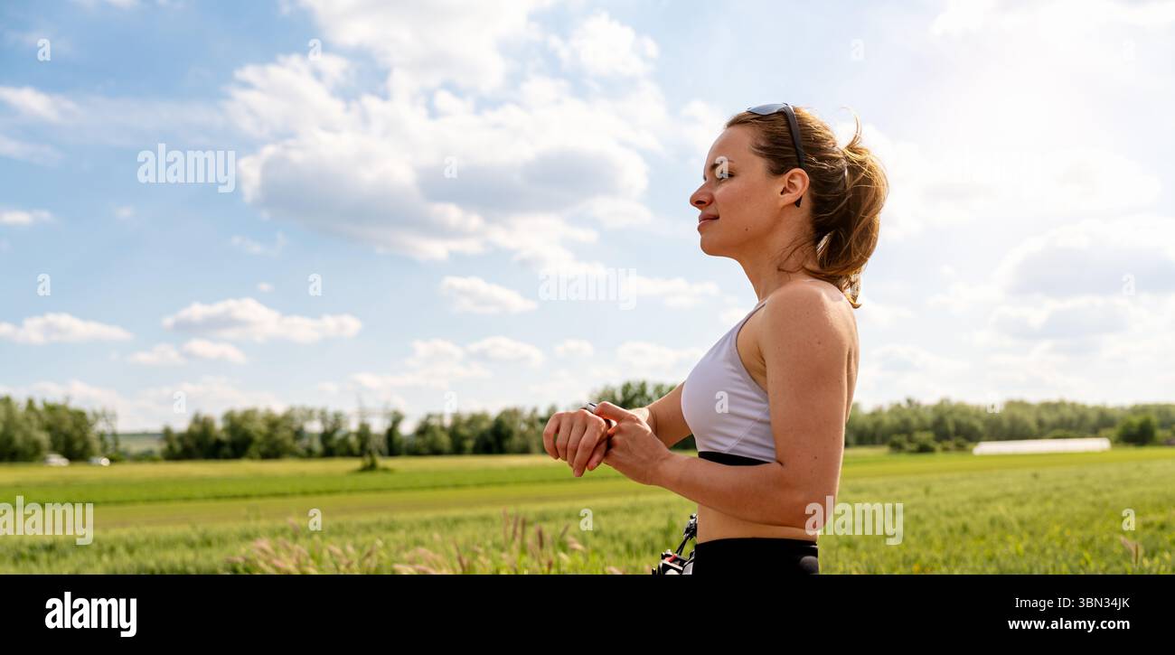 Modern fitness woman with smart watch on background of farm field in ...