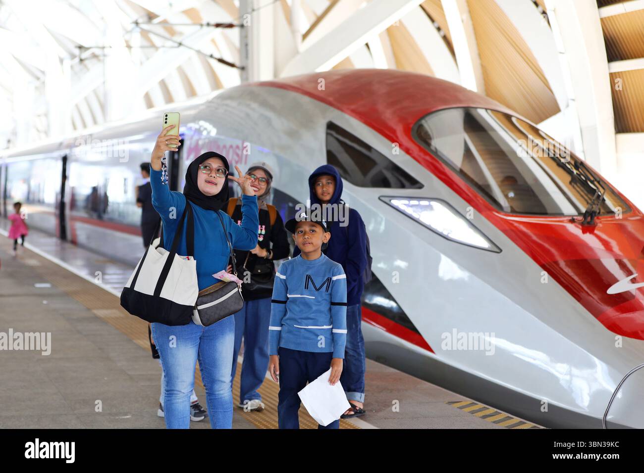 Passengers take photos in front of the train at Halim Station in ...