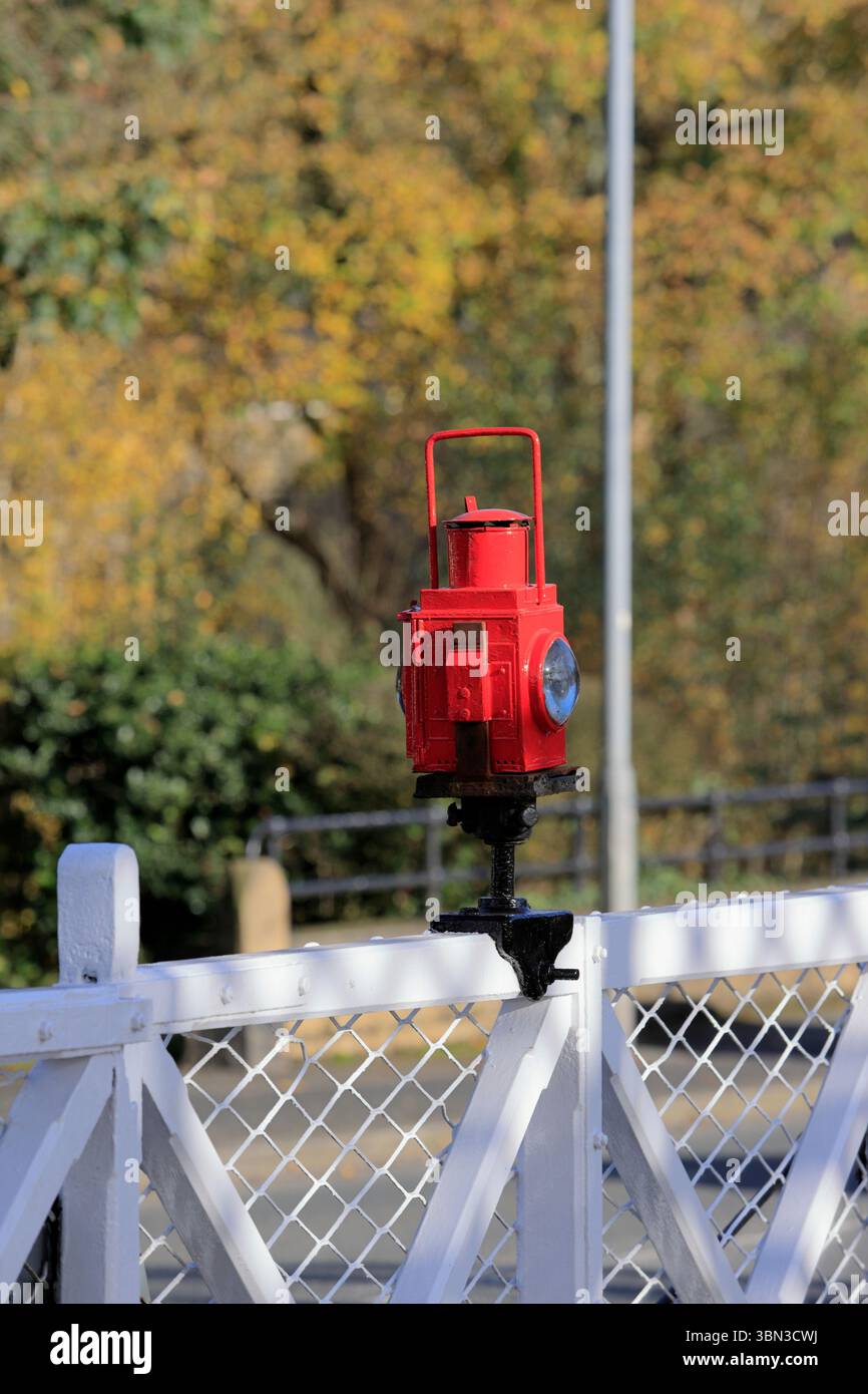 Red warning lamp mounted on wooden railway level crossing gates at east ...