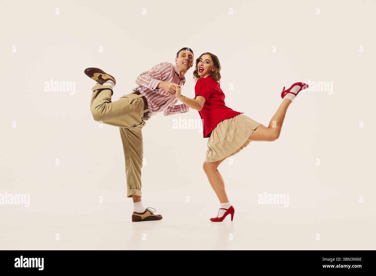 Retro couple joyfully performing energetic lindy hop dance moves on ...