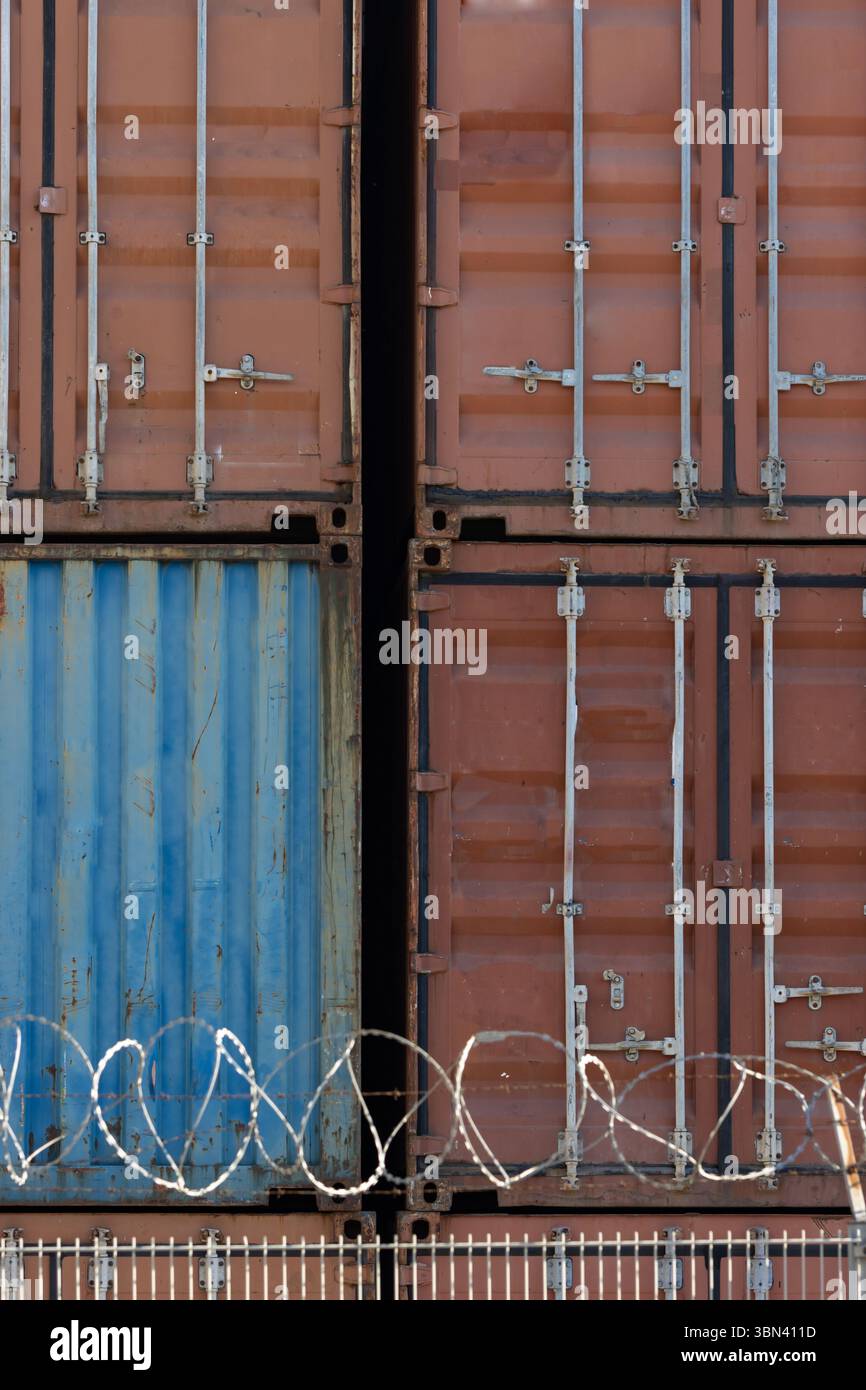 Multi colored cargo containers behind the wire fence Stock Photo - Alamy