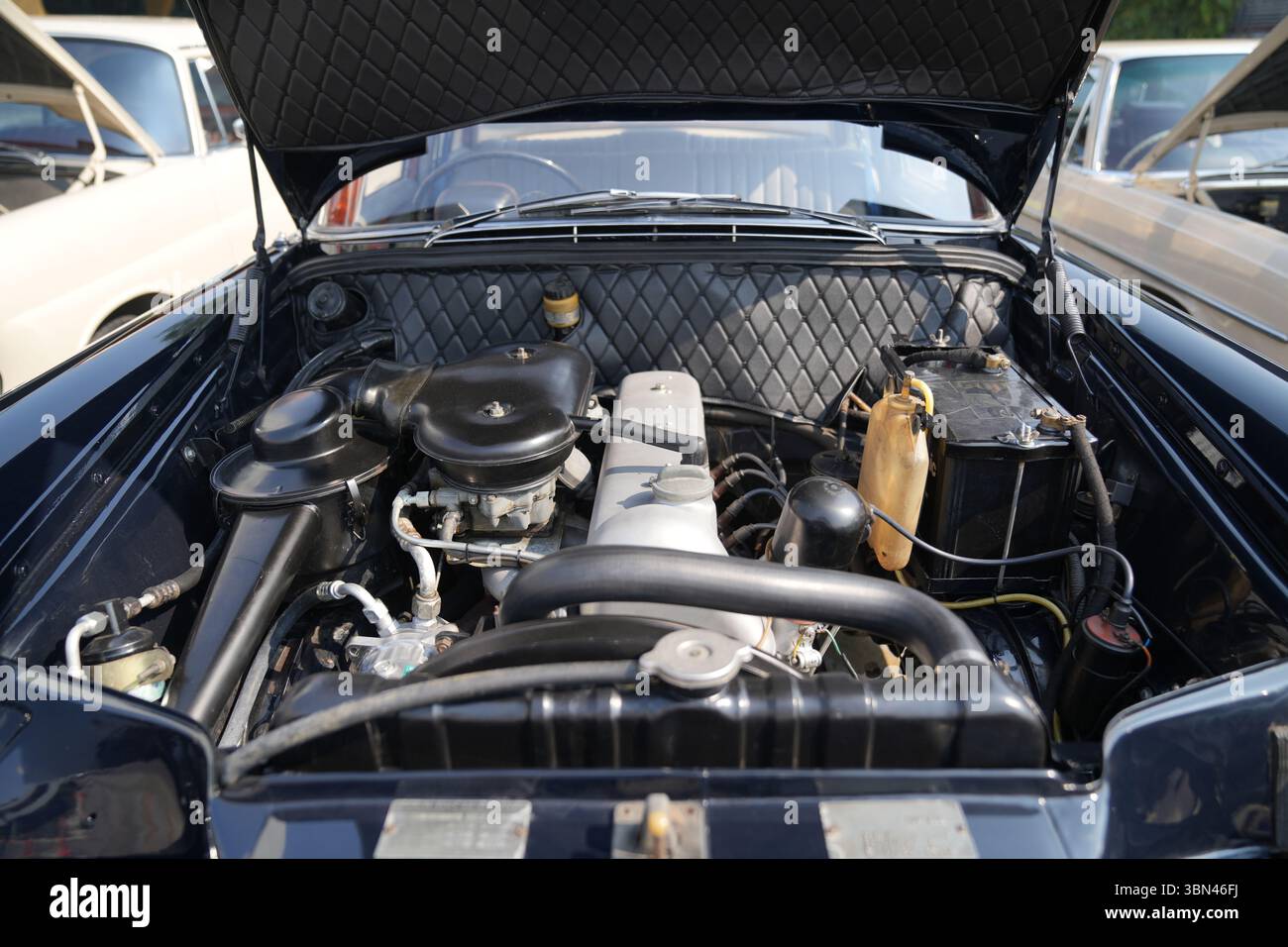 The engine and battery compartment of a classic car, with its detailed ...