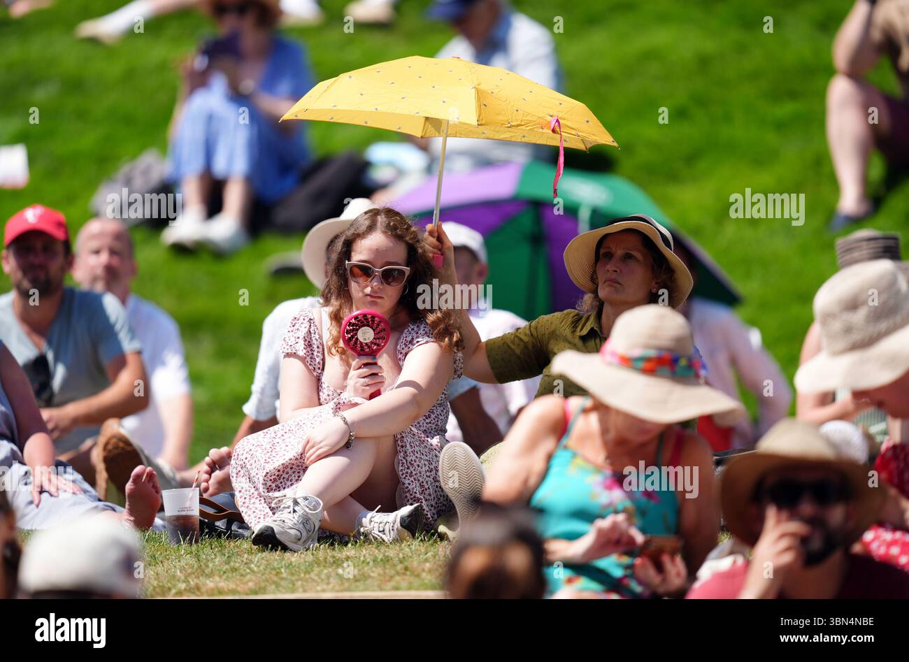Spectators on the hill shelter from the sun on day one of the 2025 ...