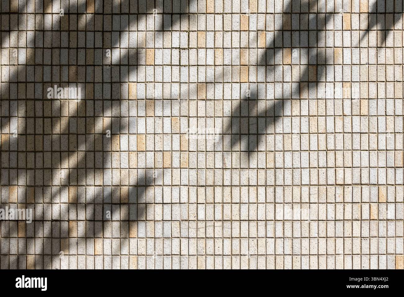 Shadow patterns on a tiled wall, creating a blend of natural light and ...