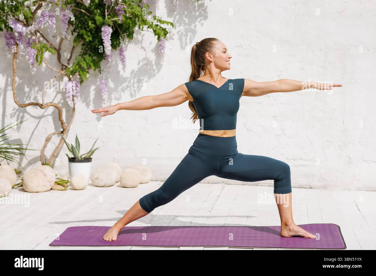 Fit woman practicing warrior yoga pose outdoors to improve flexibility ...