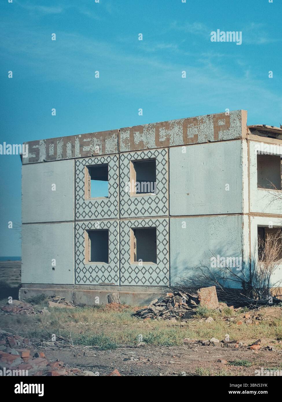 Photo of a crumbling two-story Soviet building with faded "50 years of ...