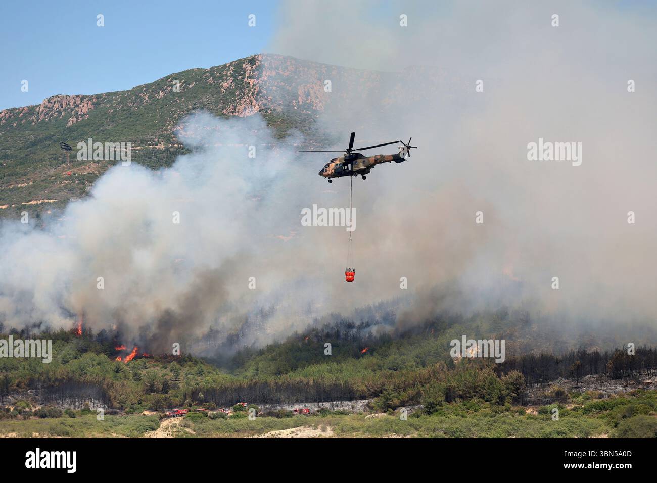 A helicopter sprays water to extinguish a fire in Seferihisar, near ...