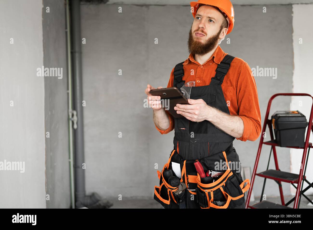 builder with tablet and tools in belt in the room. People, technology ...