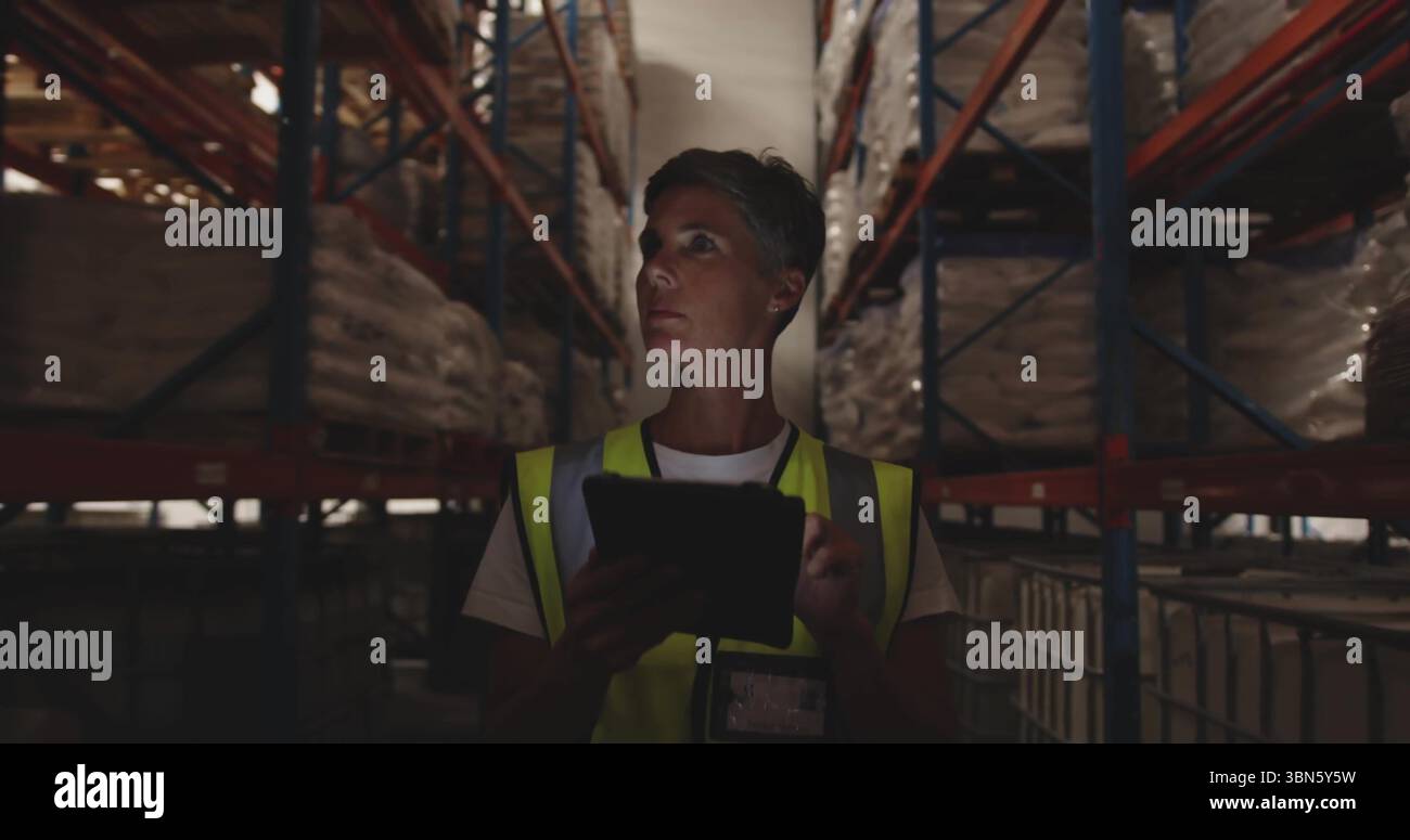 Inspecting warehouse worker checking rack stock inside warehouse aisle ...