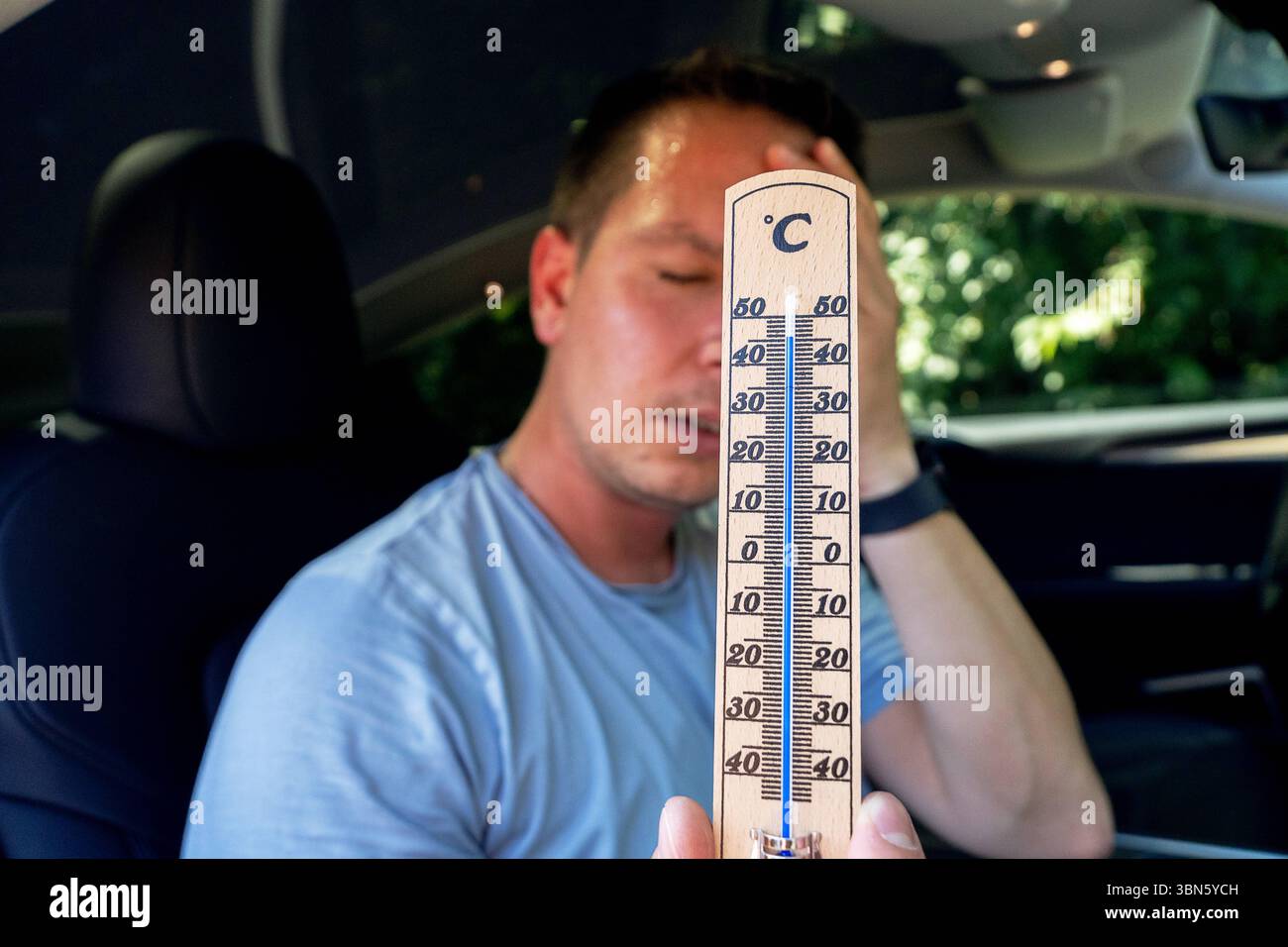 Bavaria, Germany - June 30, 2025: A man sits exhausted in an overheated ...