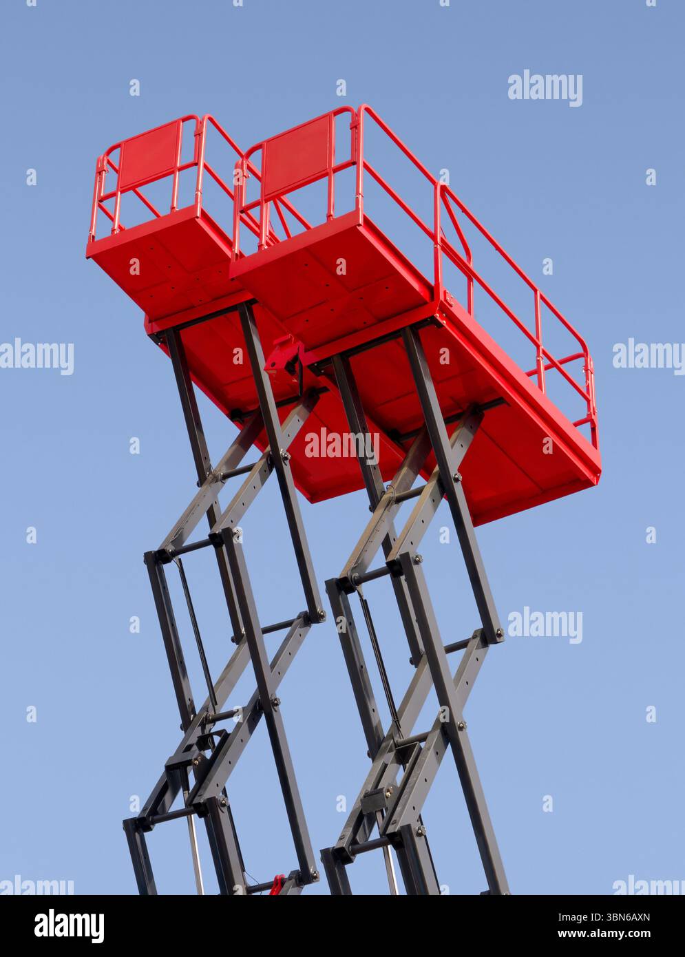 Group of red scissor lifts on a clear blue sky background, low angle ...