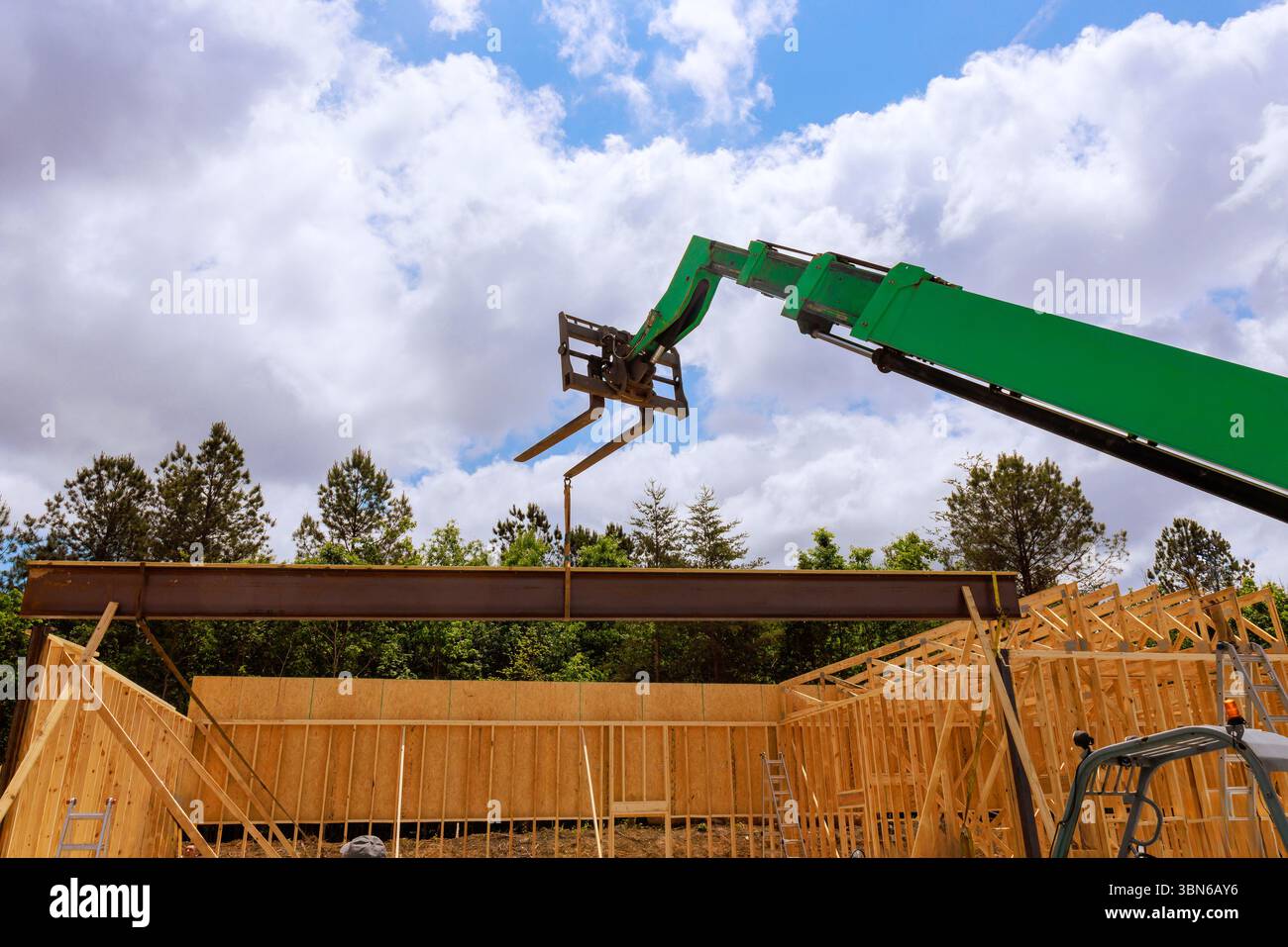 Construction crew uses telehandler crane to hoist steel beam into place ...