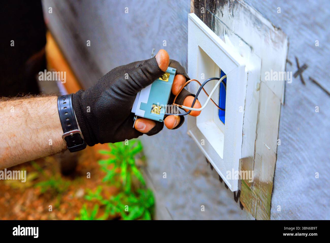 Technician works on installing an electrical outlet outdoors in ...