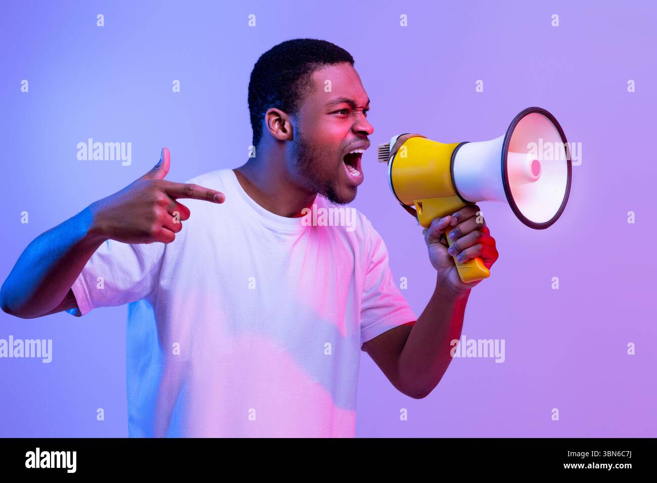 Full length portrait of aggressive young man shouting using megaphone ...