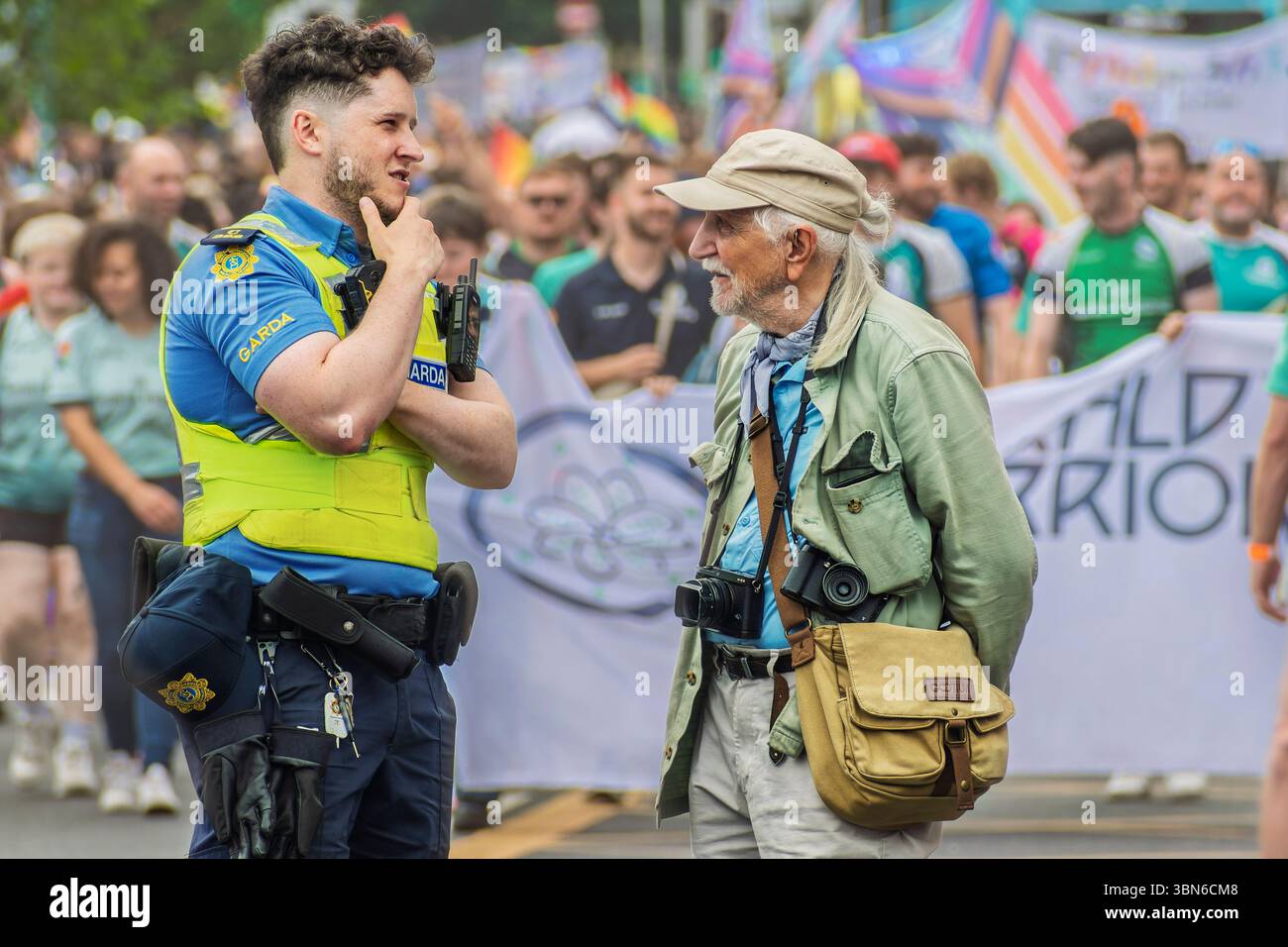 Veteran photographer, with cameras , peacefully converses with a Garda ...