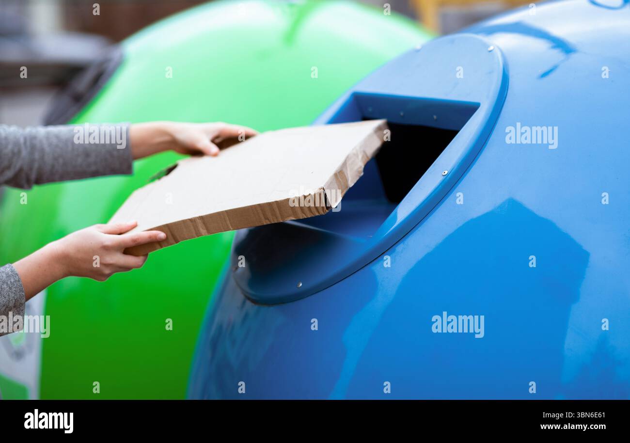 Waste Sorting. Lady throwing cardboard box into blue recycle bin ...