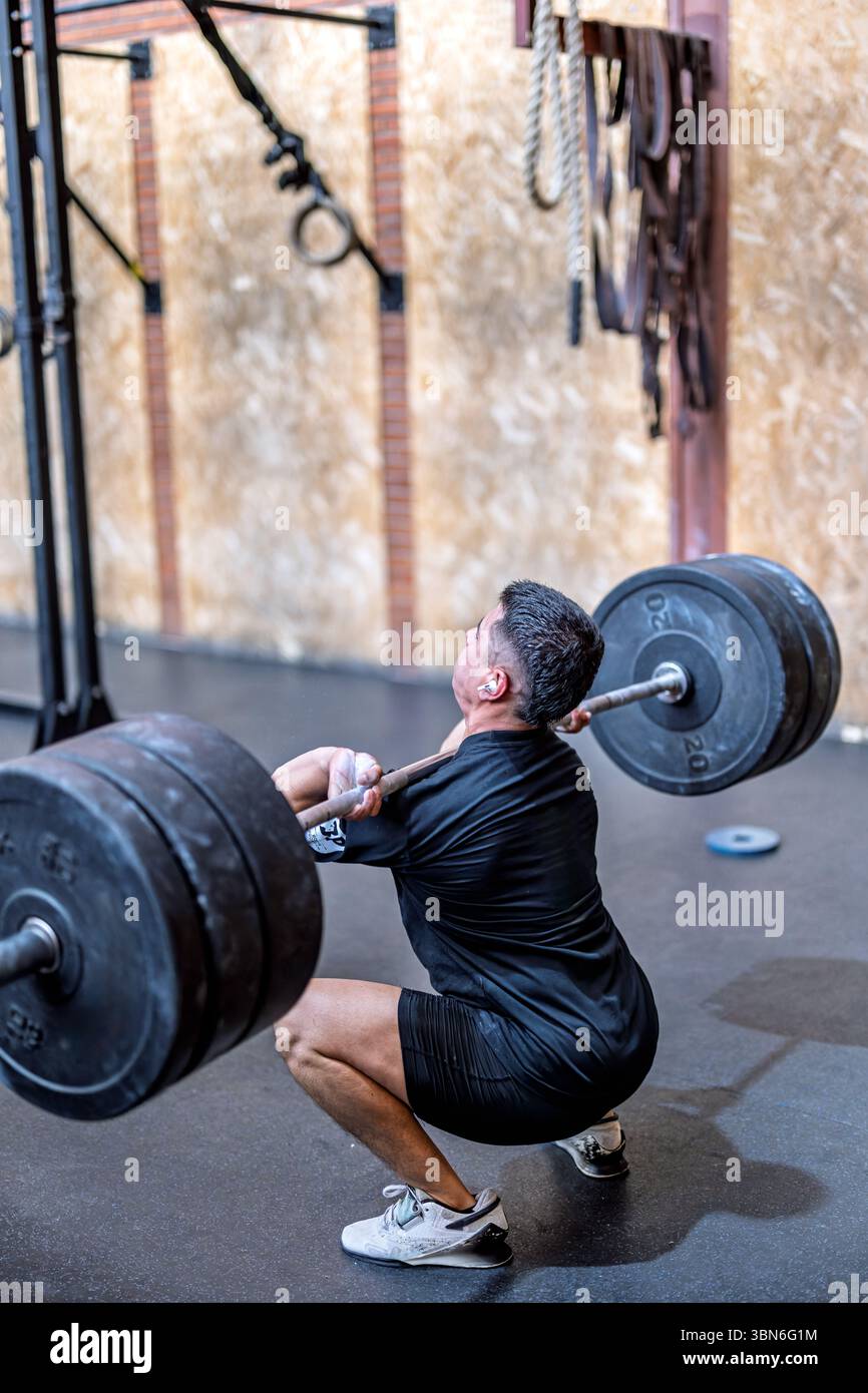 A weightlifting athlete is executing a squat with a heavy barbell in a ...