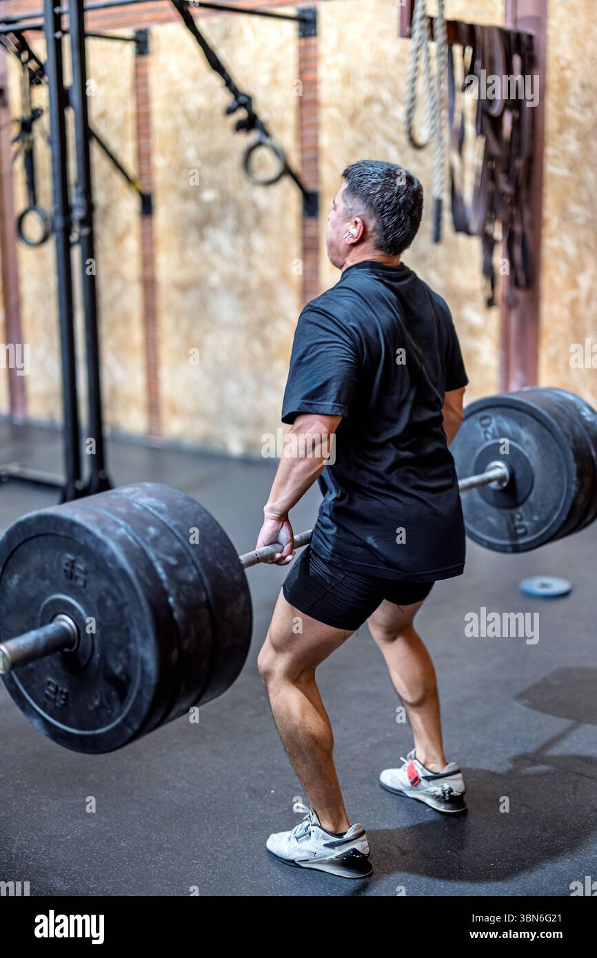 A weightlifting athlete focuses on lifting heavy weights in a gym. The ...