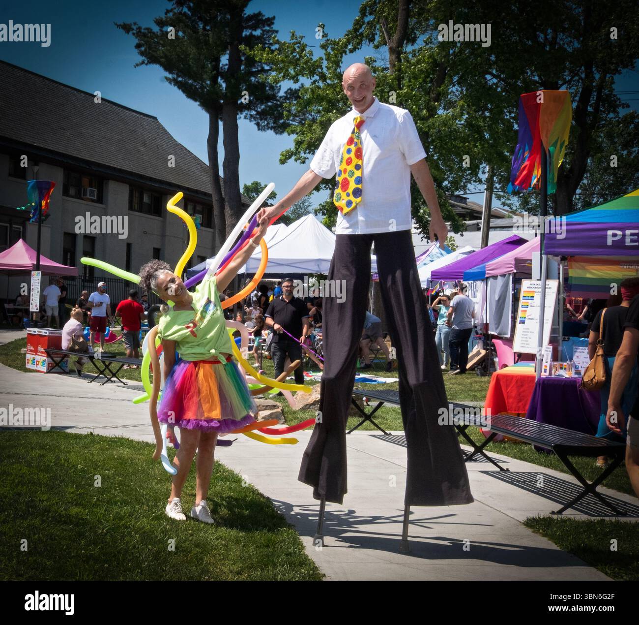 At the Peekskill Pride Family Pride in the Park event, a man on stilts meets a lady wearing ...