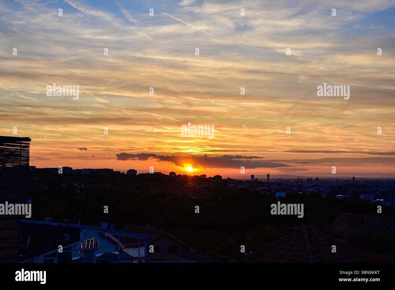 Sunset illuminates city outlines under a dramatic sky, clouds painted ...