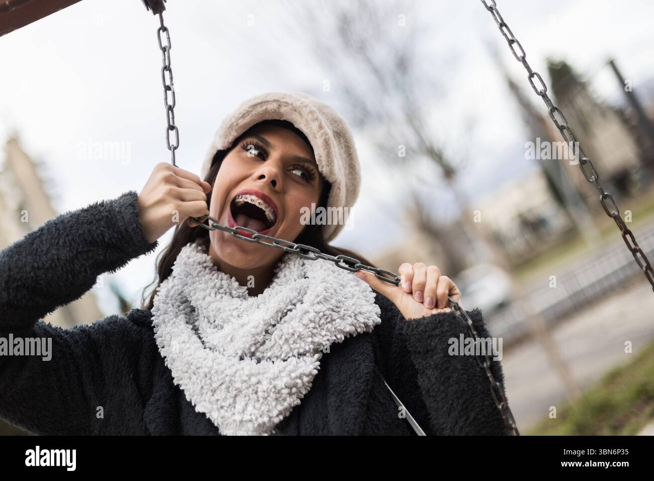 A cheerful young woman with braces wearing a cozy scarf and beanie ...