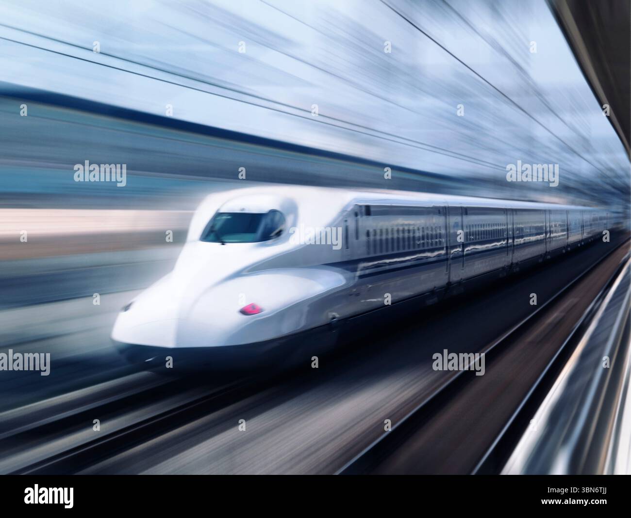 Shinkansen high-speed bullet train N700 series Nozomi passing a platform blurred from motion ...