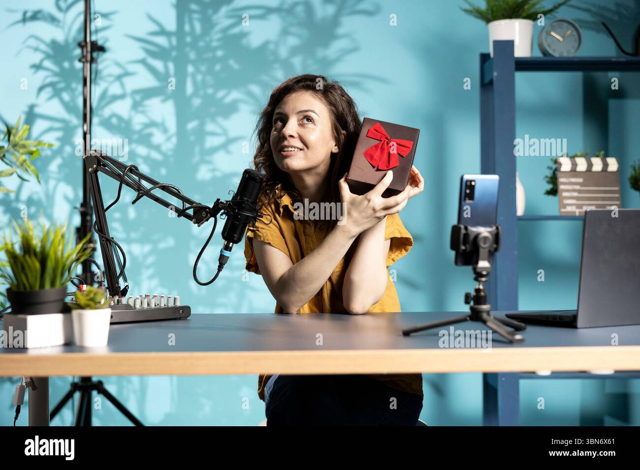 Social media influencer shaking gift box, curious to hear what is ...