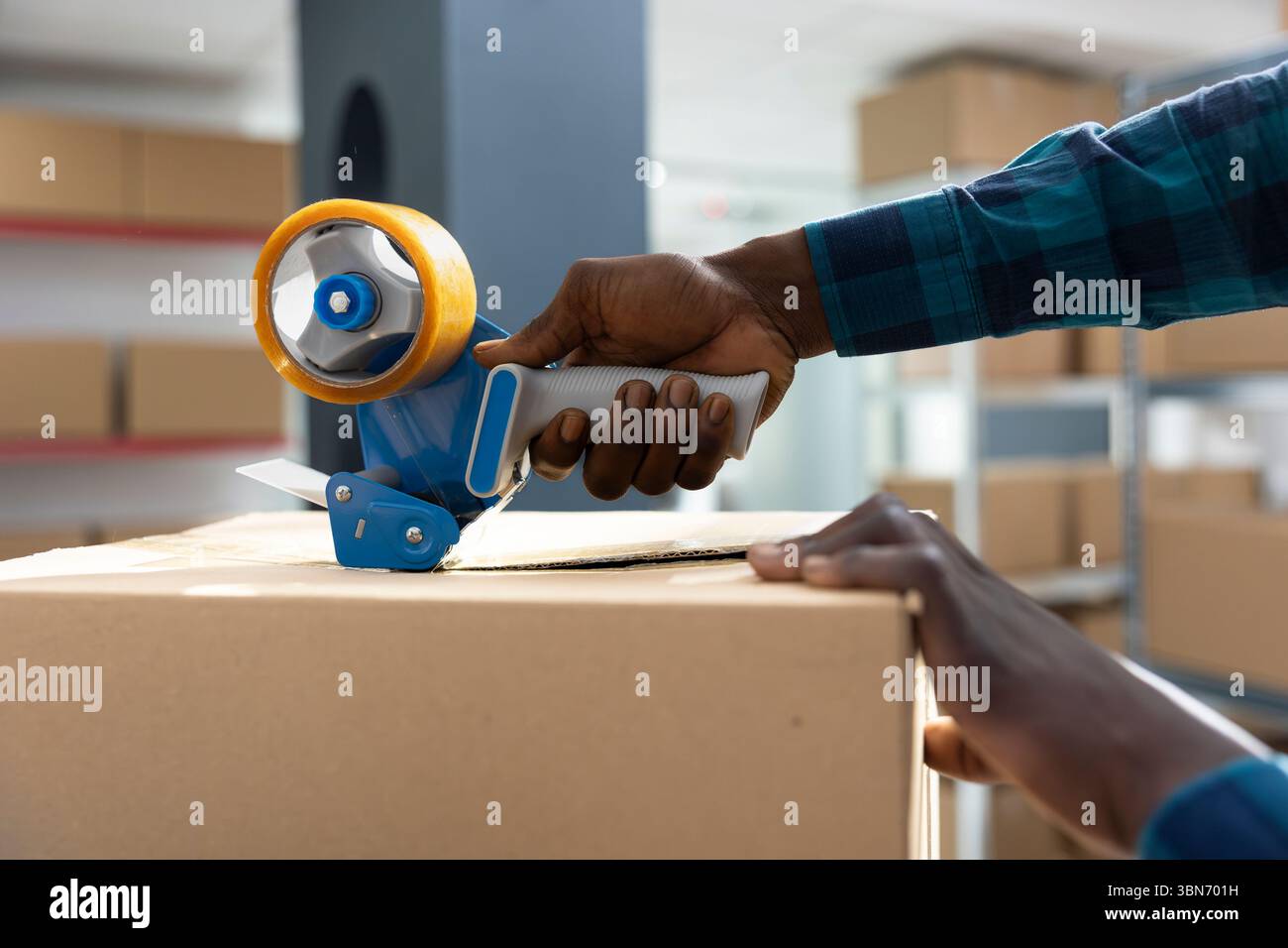 Factory worker applies adhesive tape to boxes while attaching air ...
