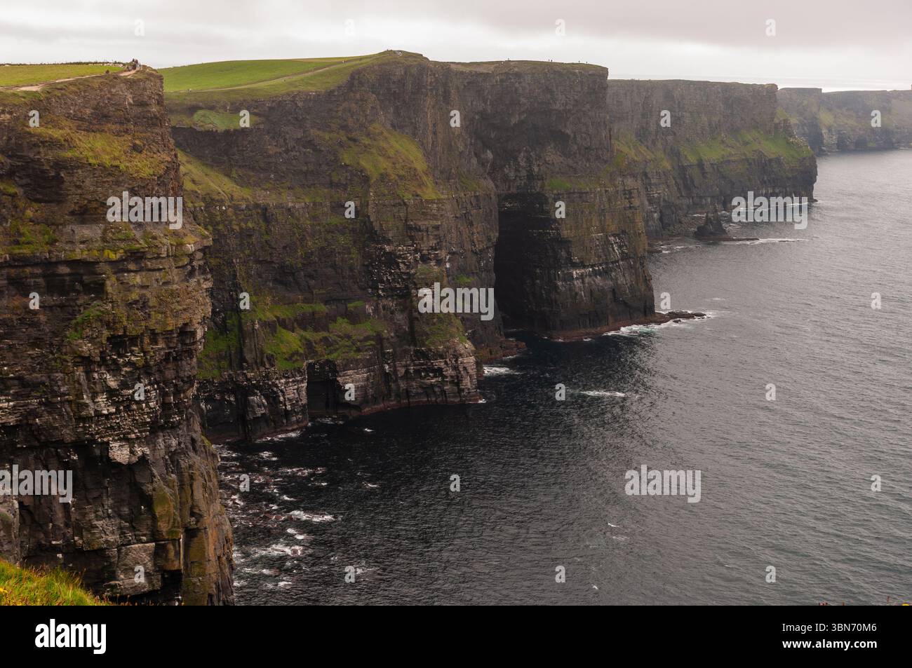 The ocean is calm and the cliffs are green. The cliffs are rocky and ...