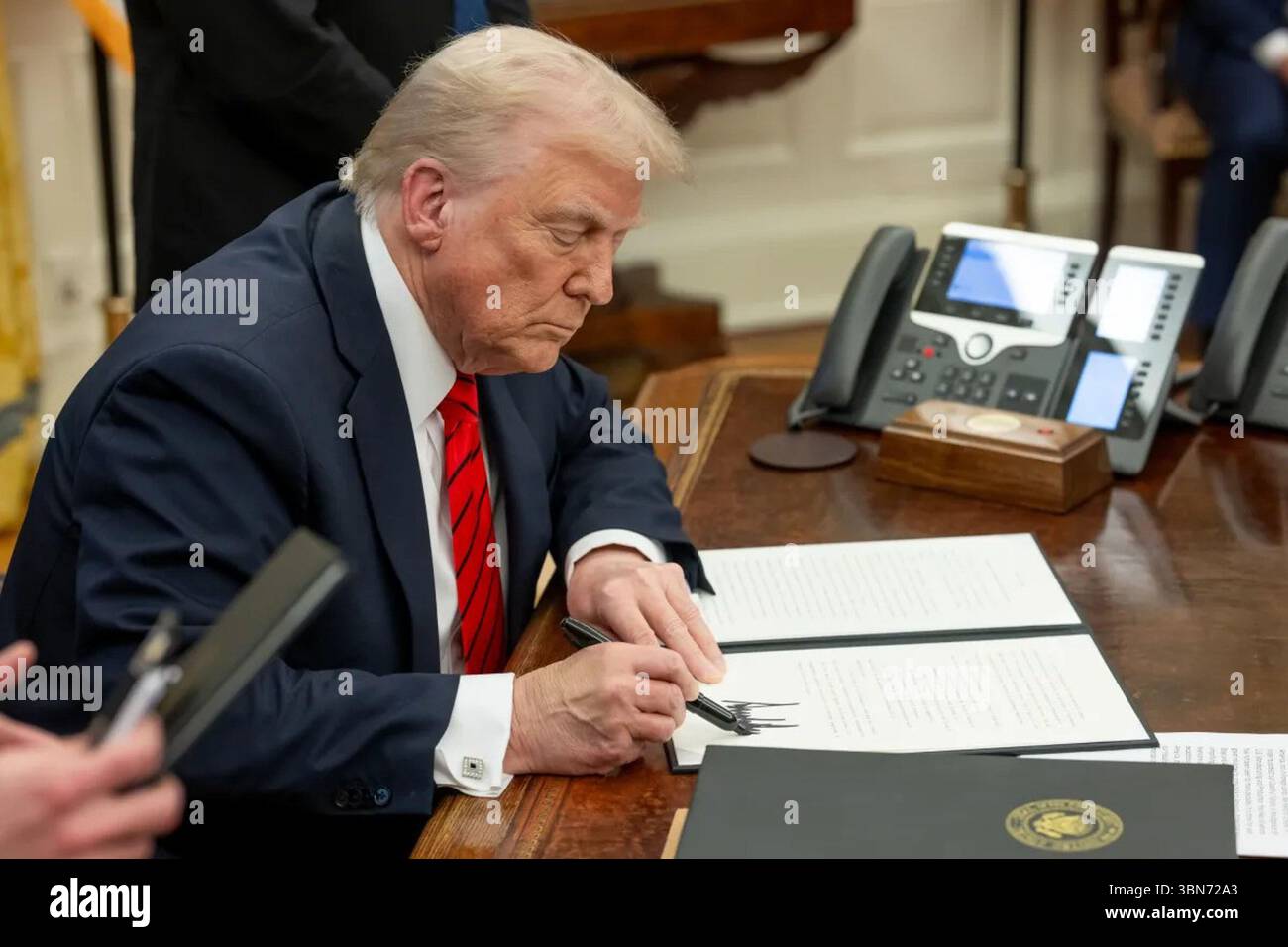 President Trump signs executive orders at his desk in the Oval Office ...