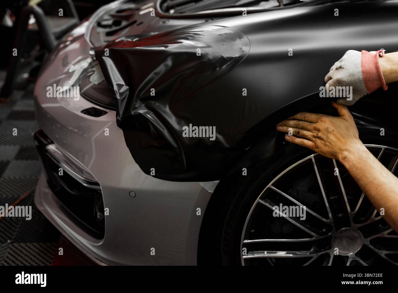 Matte black vinyl wrapping around car with smooth alignment over curves ...