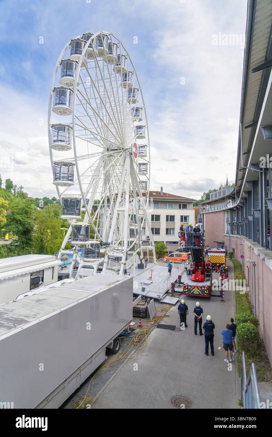 Fire brigade operation with a high Ferris wheel next to buildings with ...